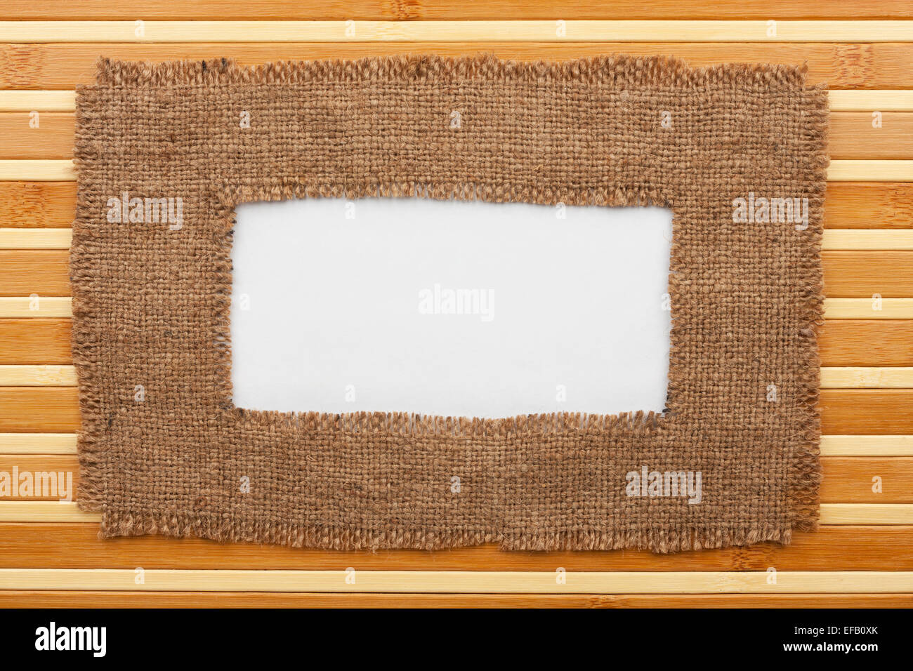 Frame made of burlap with white background lying on a bamboo mat, with ...