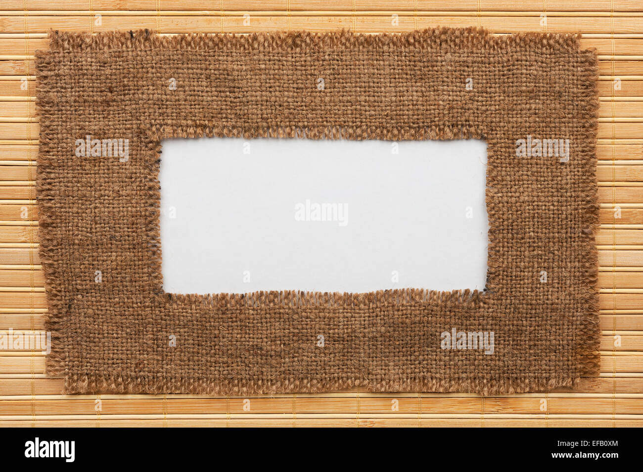 Frame made of burlap with white background lying on a bamboo mat, with ...