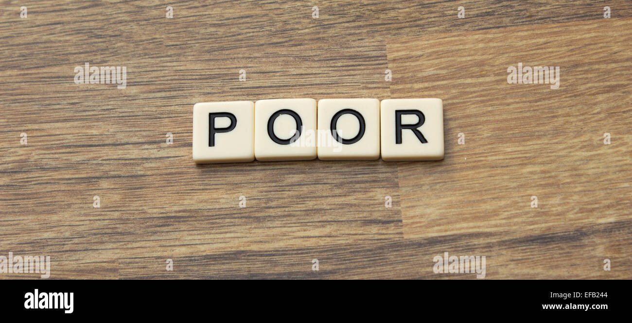 The word poor written in tiles on a wooden surface Stock Photo - Alamy