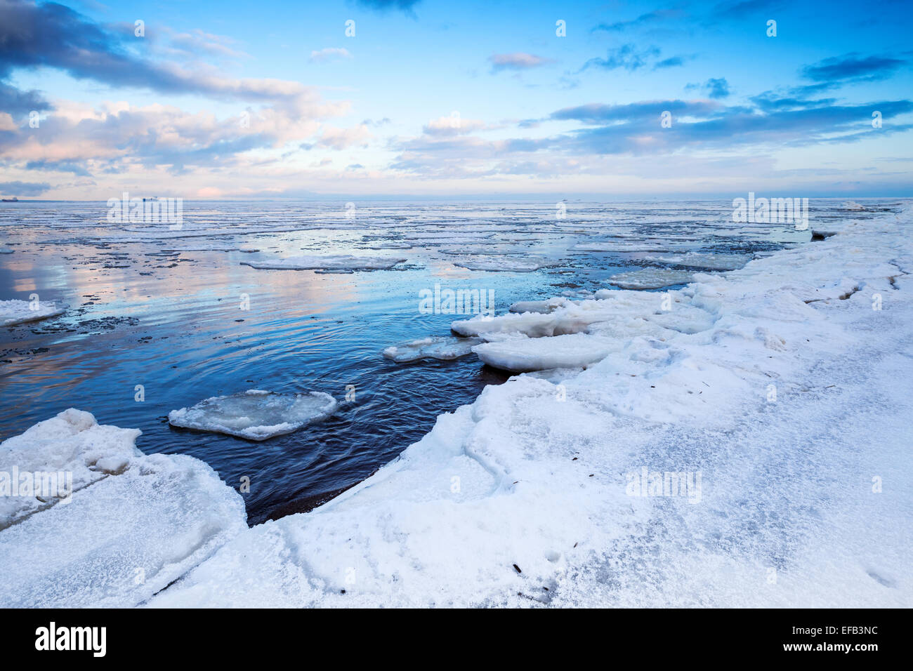 Winter coastal landscape with floating ice fragments on still water ...