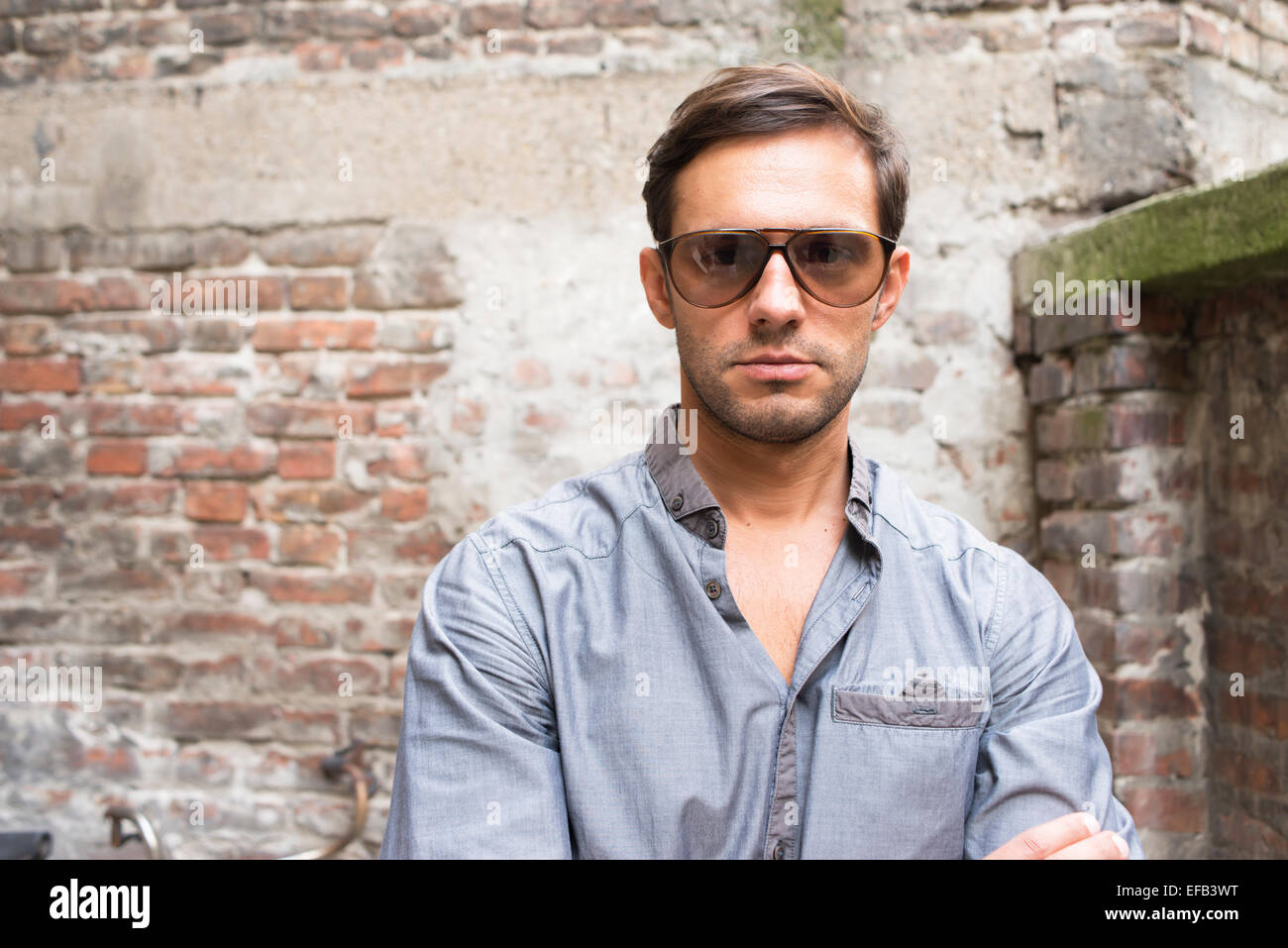Casual young man stands with his back against a brick wall Stock Photo ...