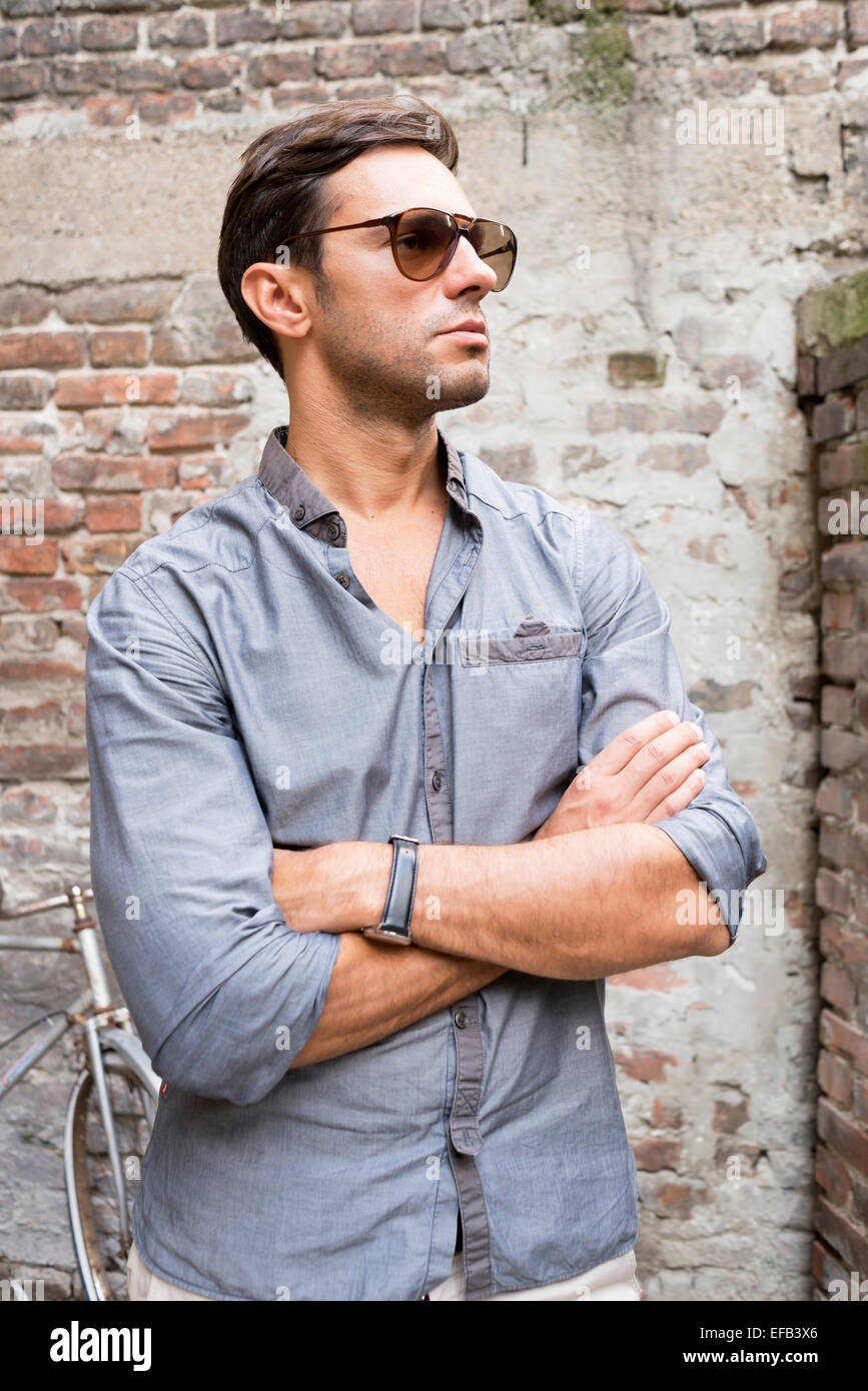 Casual young man stands with his back against a brick wall Stock Photo ...