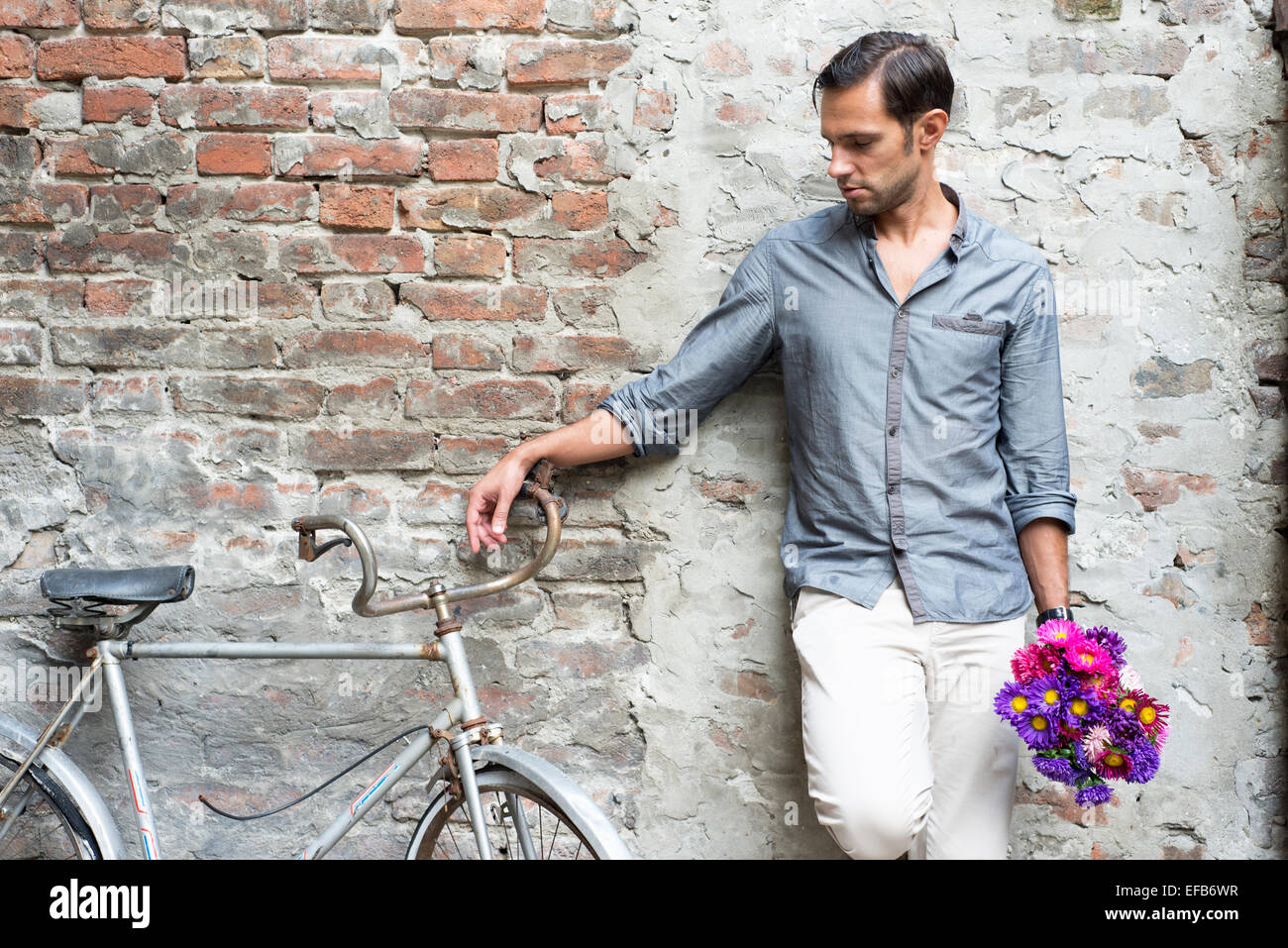 Casual young man stands with his back against a brick wall Stock Photo ...