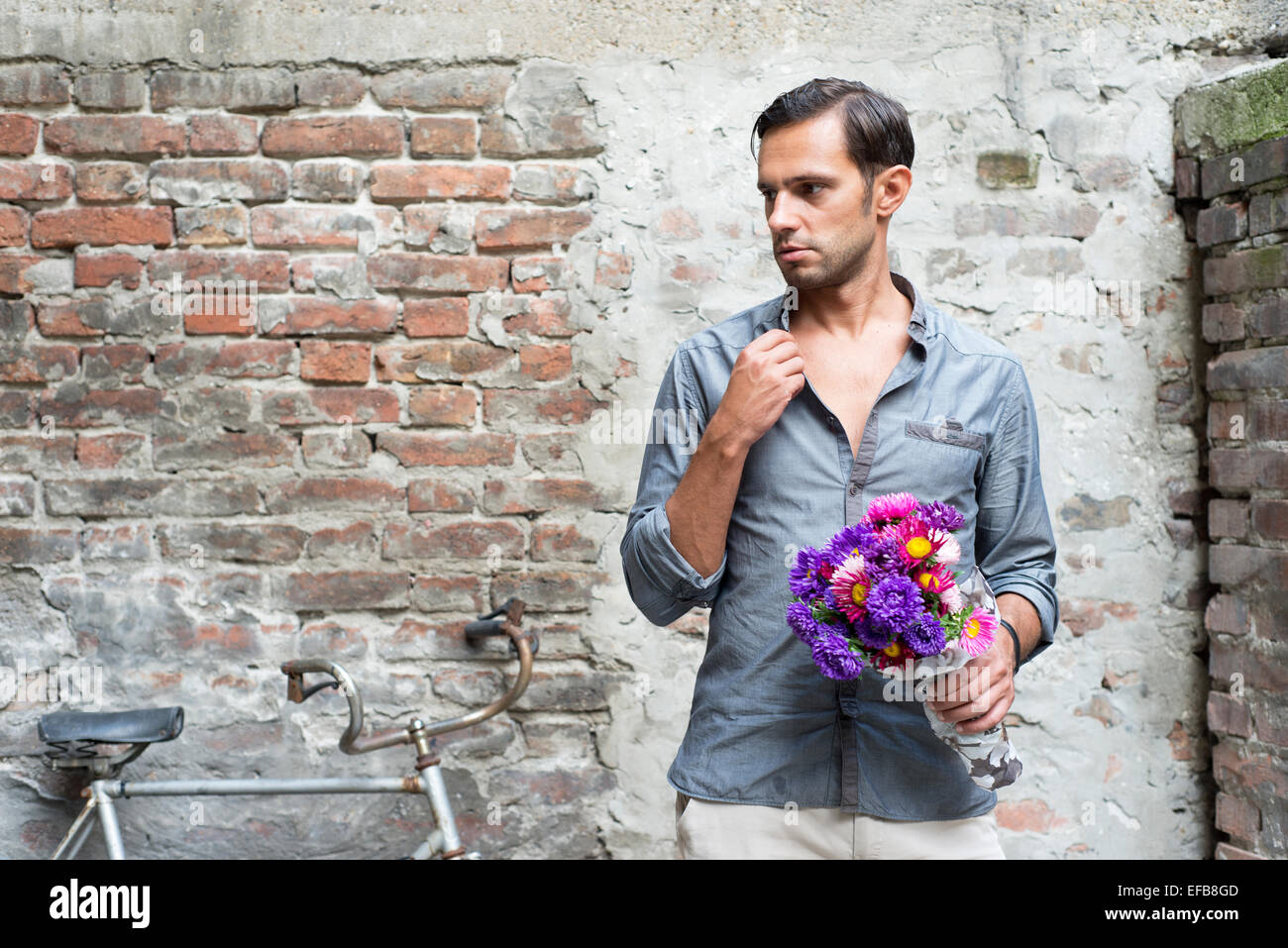 Casual young man stands with his back against a brick wall Stock Photo ...