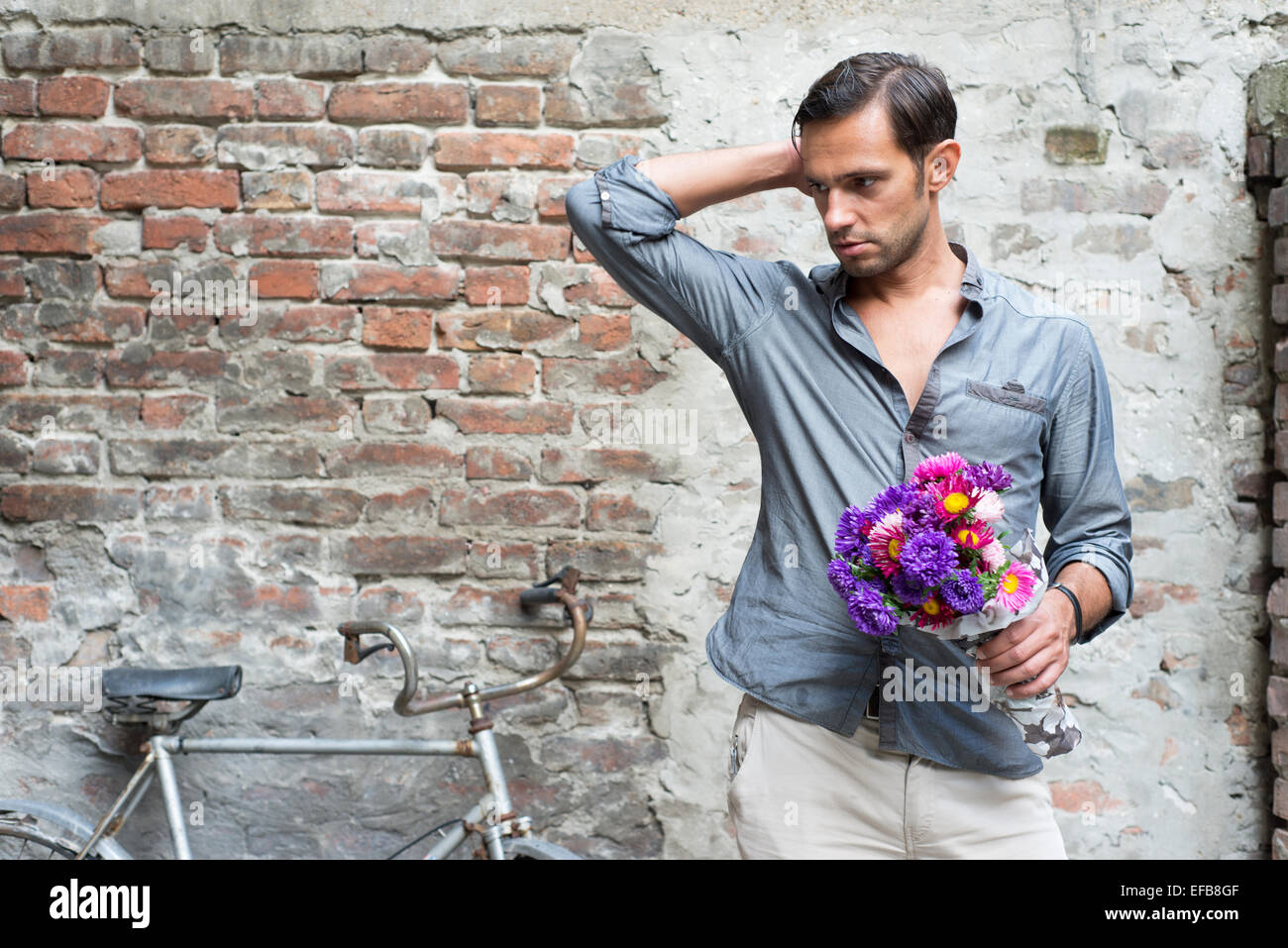 Casual young man stands with his back against a brick wall Stock Photo ...