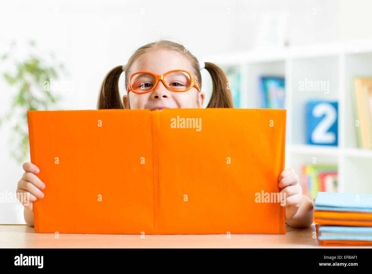 clever kid little girl behind of open book indoor Stock Photo - Alamy