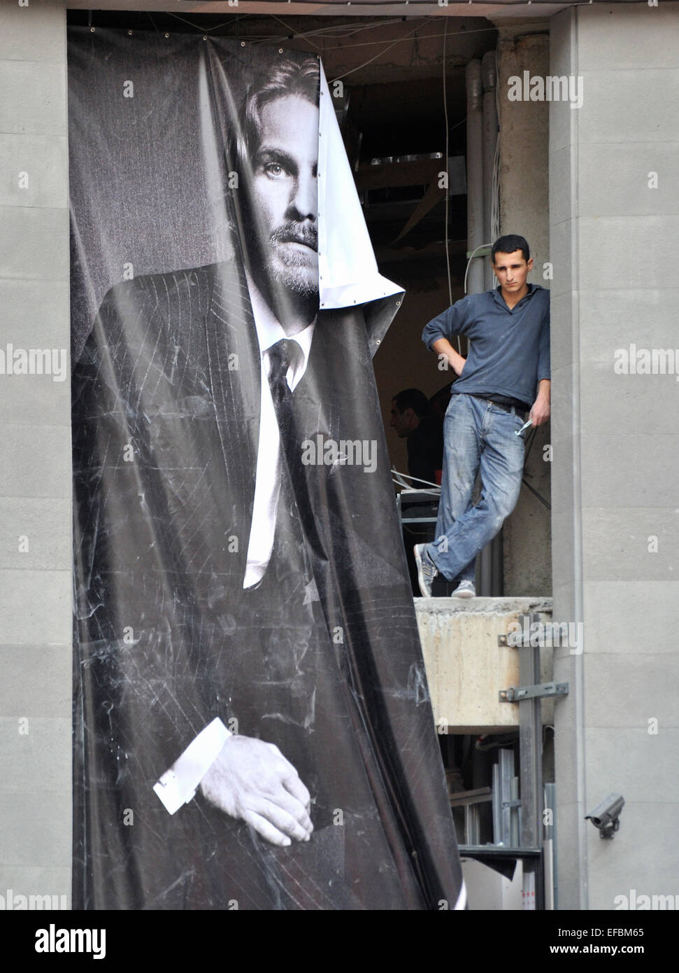 Worker taking a break while changing billboard posters at high street ...