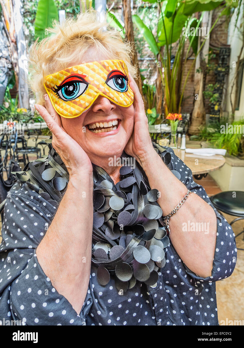 A bizarre eye cover mask worn by a female senior citizen seated and ...