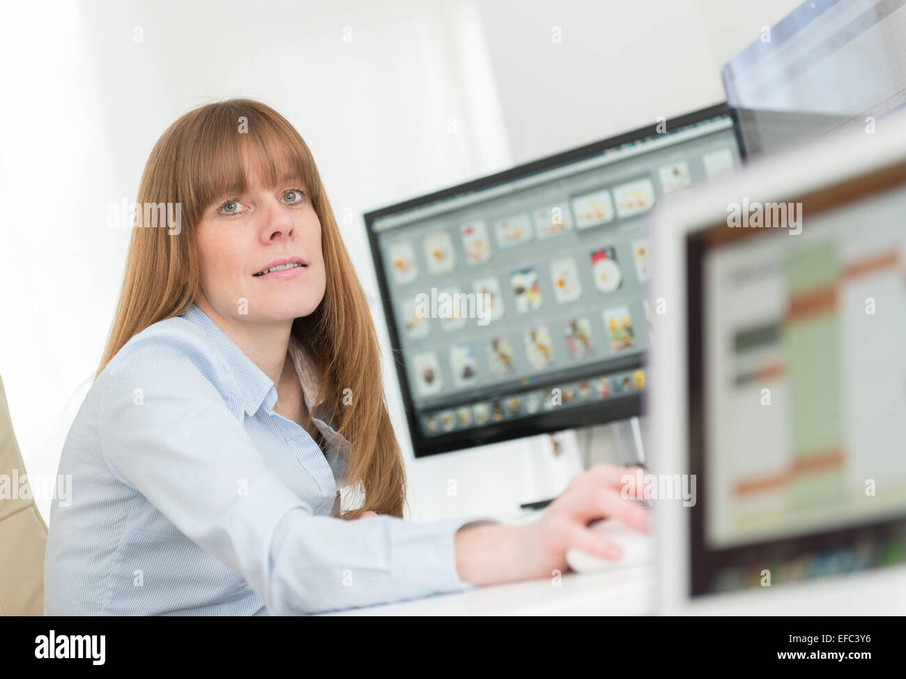 A woman working in an office at a desk, editing a magazine Stock Photo ...