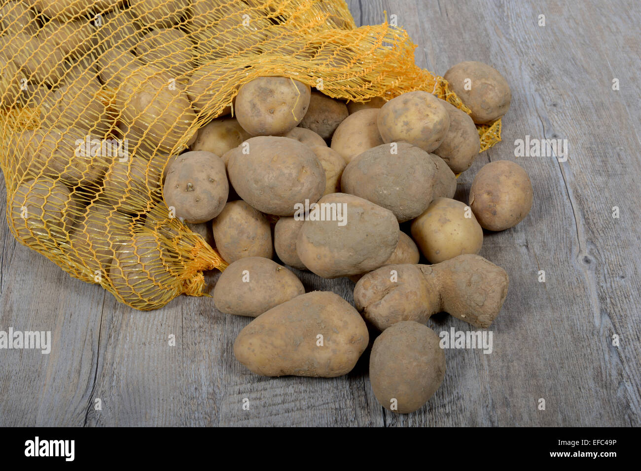 bag of potatoes sitting on a wooden table Stock Photo - Alamy