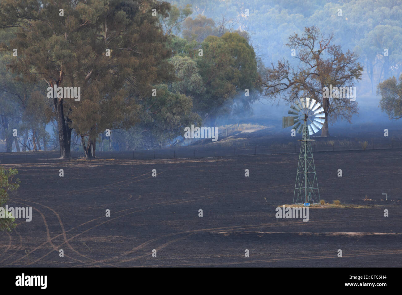 A photograph of a windmill in the aftermath of a bush fire on a dry ...