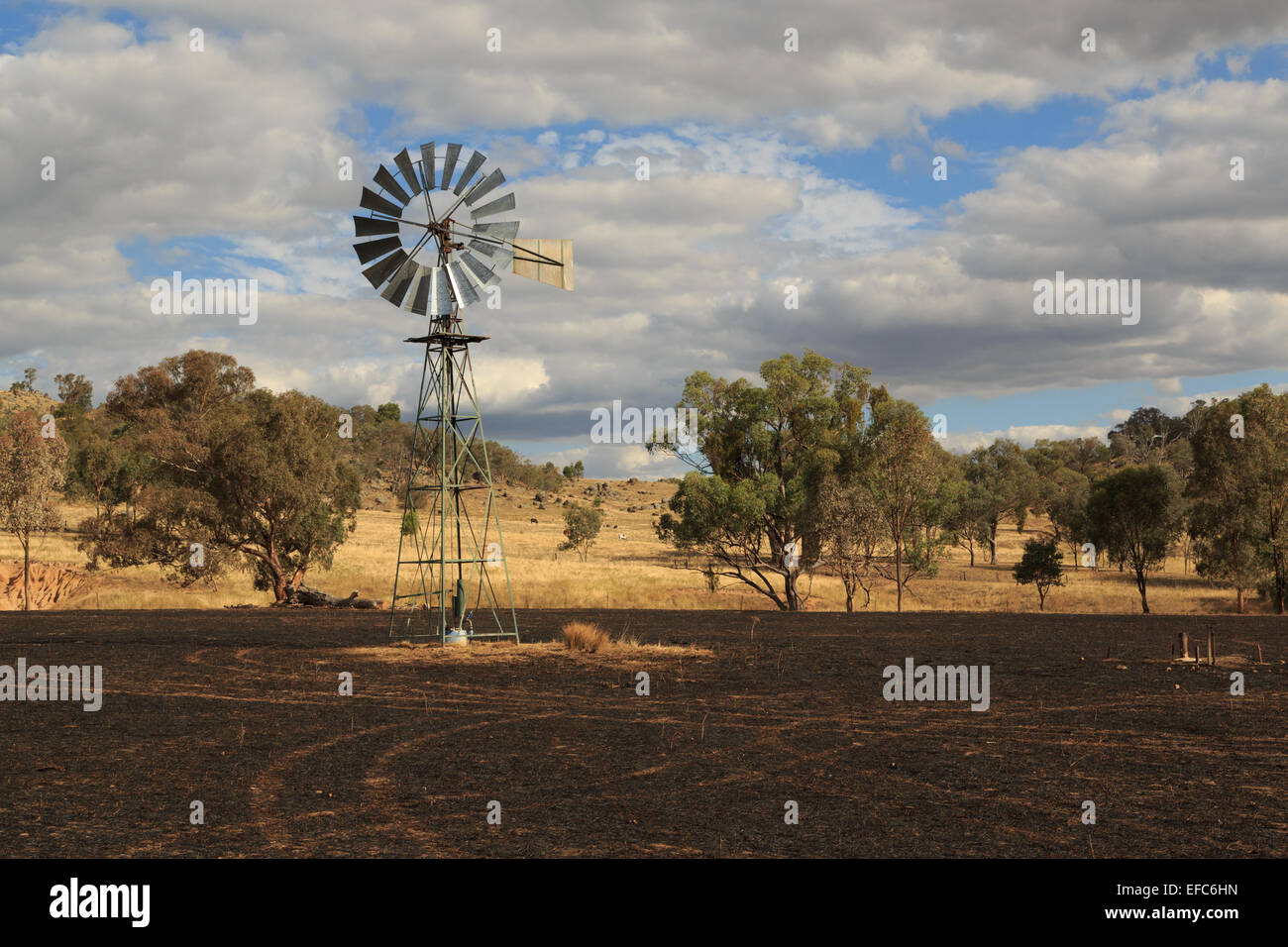 A photograph of a windmill in the aftermath of a bush fire on a dry ...