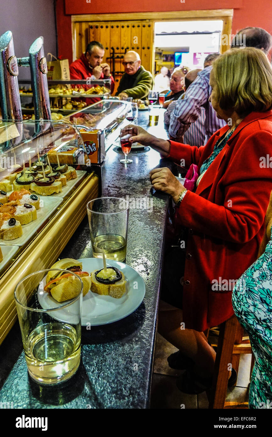 Tapas bar interior in Spain. Customers stand at counter eating pintxos ...