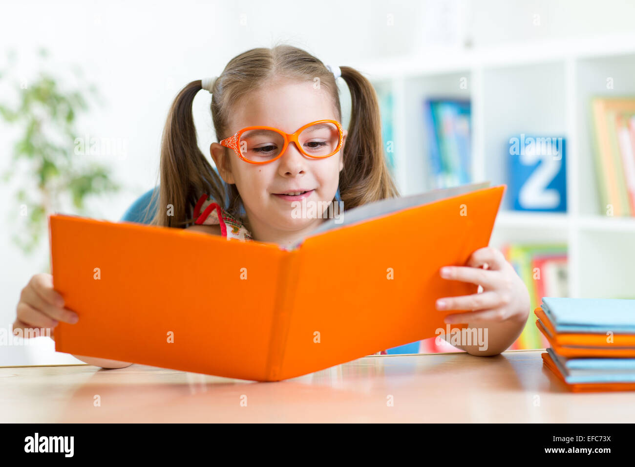 Little girl reading a book Stock Photo - Alamy