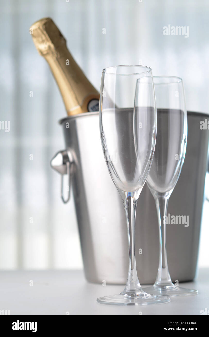 Champagne bottle in bucket with empty champagne glasses Stock Photo - Alamy