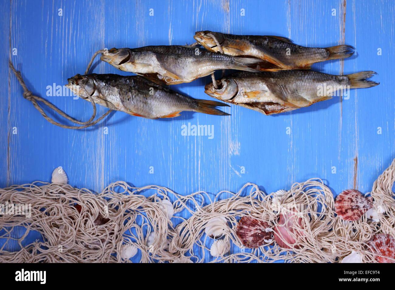 Dried rudd fish and fishing net on blue background, horizontal Stock ...