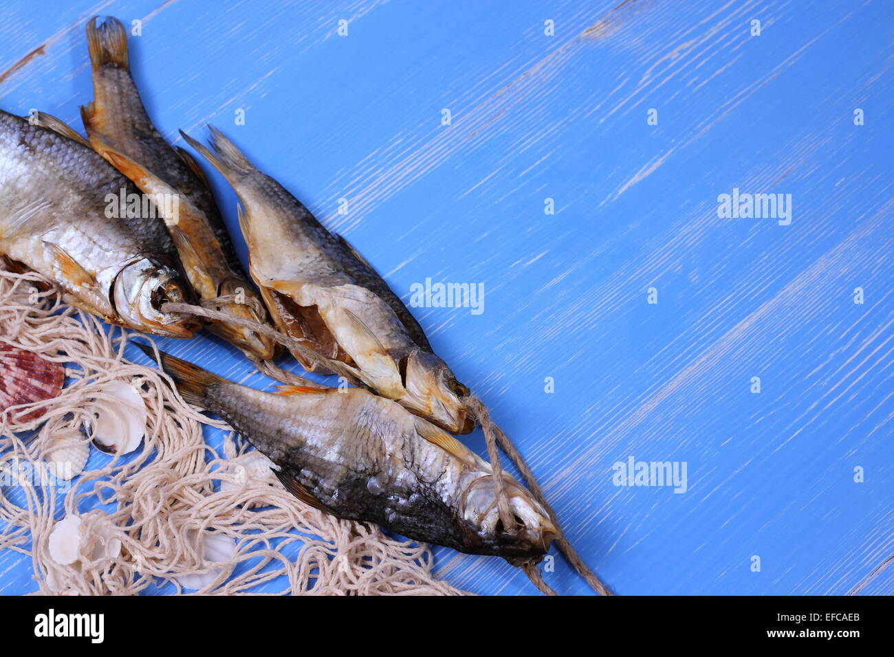 Dried rudd fish and fishing net on blue background, top view Stock ...