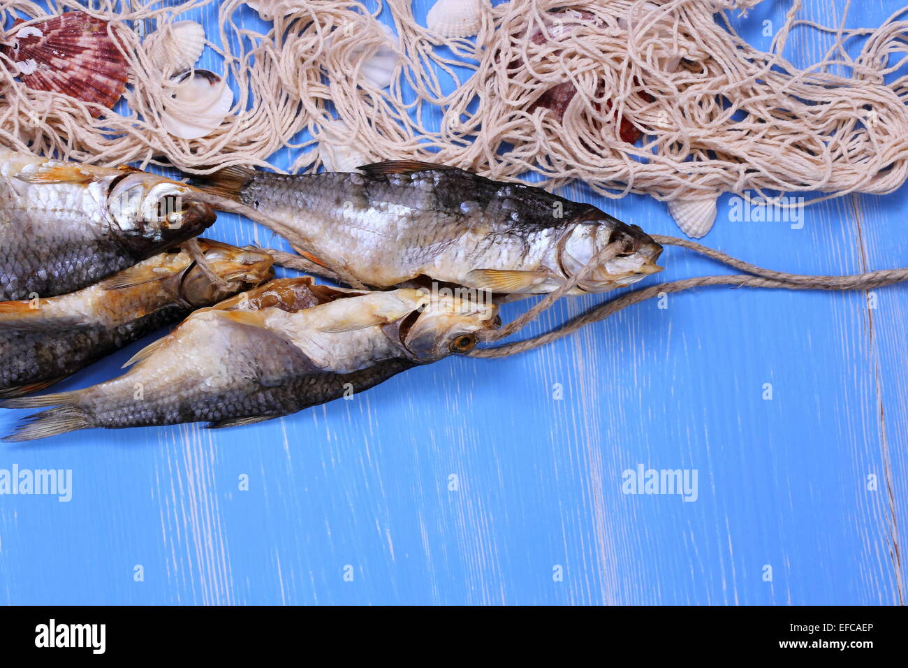 Dried rudd fish and fishing net on blue background, horizontal Stock ...