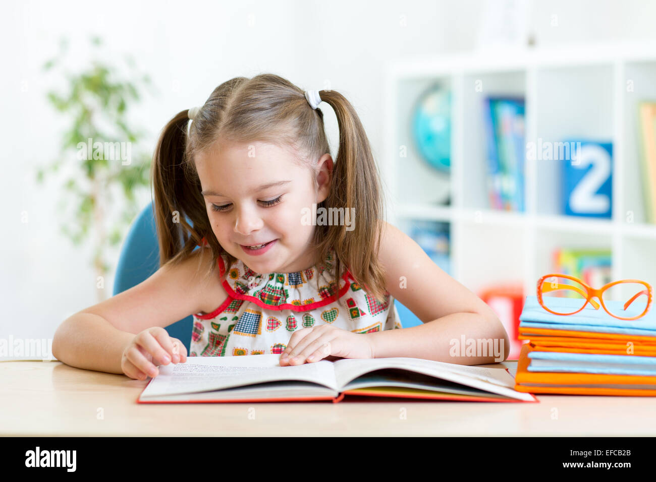 Kid girl learns to read book Stock Photo - Alamy