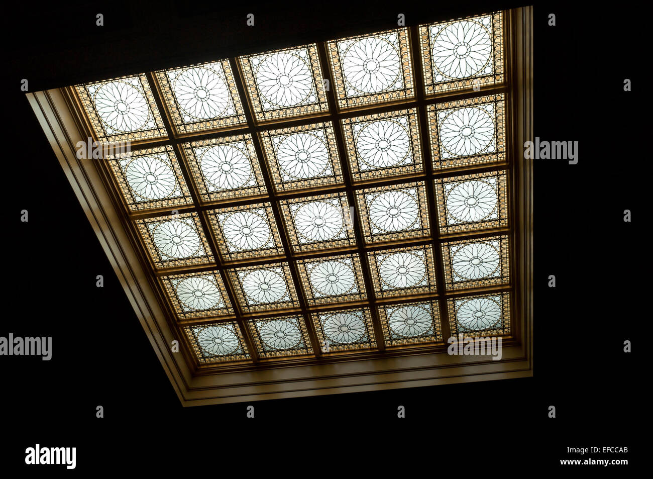Floral pattern painted glass skylight of square panes in darkened room ...