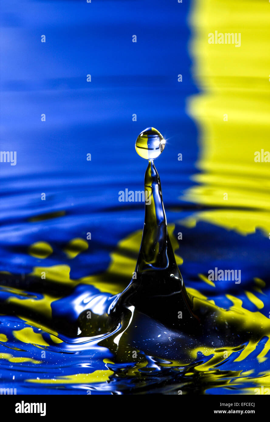 Water drop hitting the surface of water and rebounding with a colourful ...