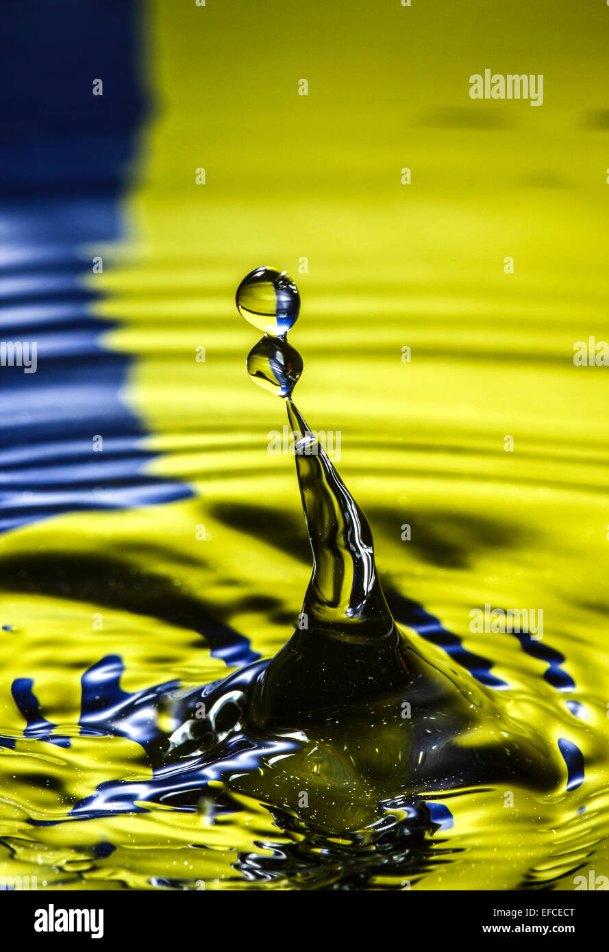 Water drop hitting the surface of water and rebounding with a colourful ...