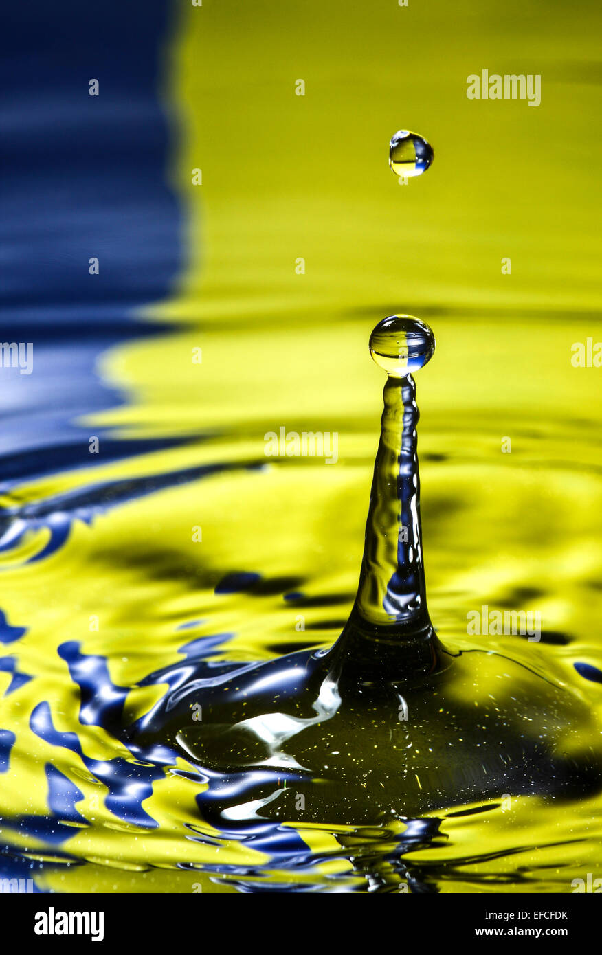 Water drop hitting the surface of water and rebounding with a colourful ...
