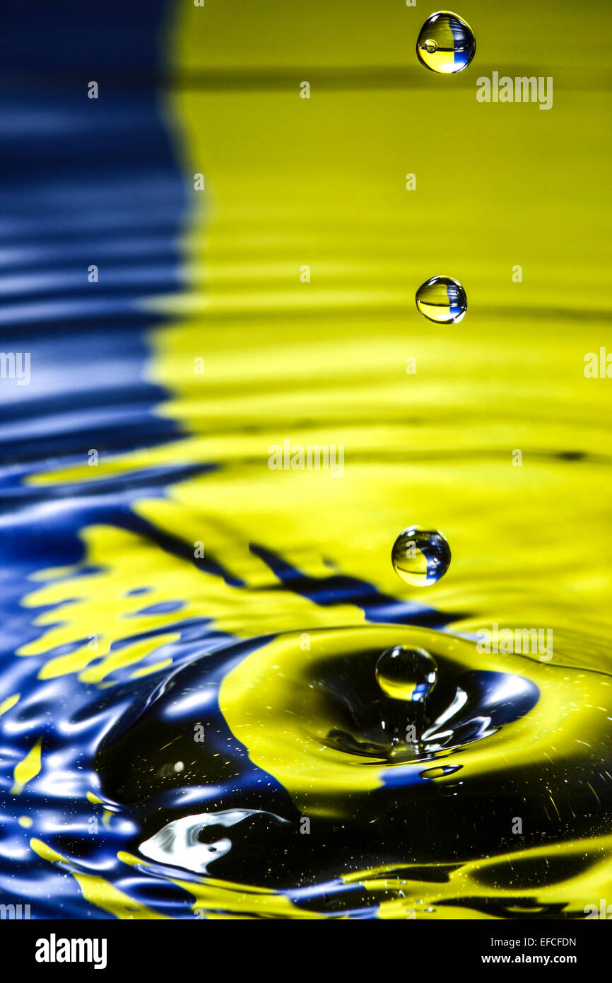 Water drop hitting the surface of water and rebounding with a colourful ...