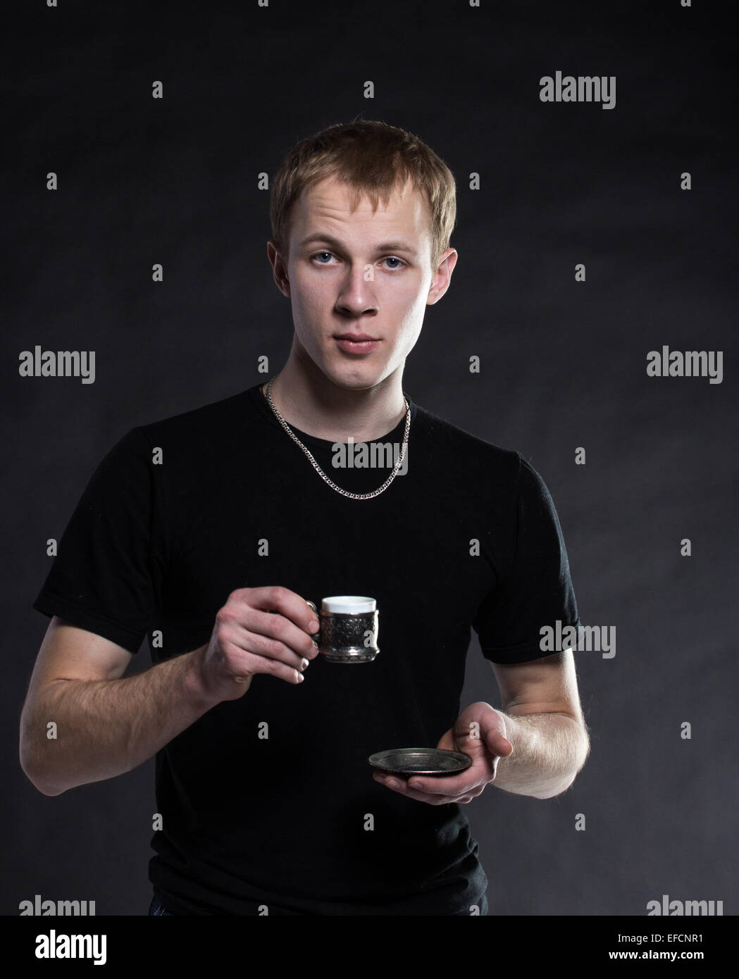 Young man drinking tea on a black background Stock Photo - Alamy