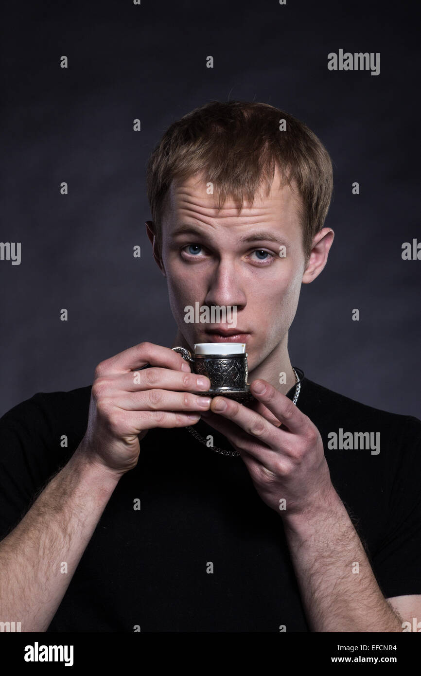 Young man drinking tea on a black background Stock Photo - Alamy