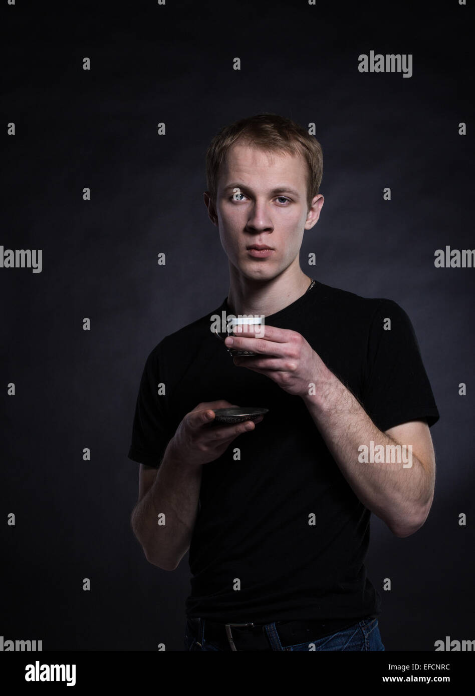 Young man drinking tea on a black background Stock Photo - Alamy