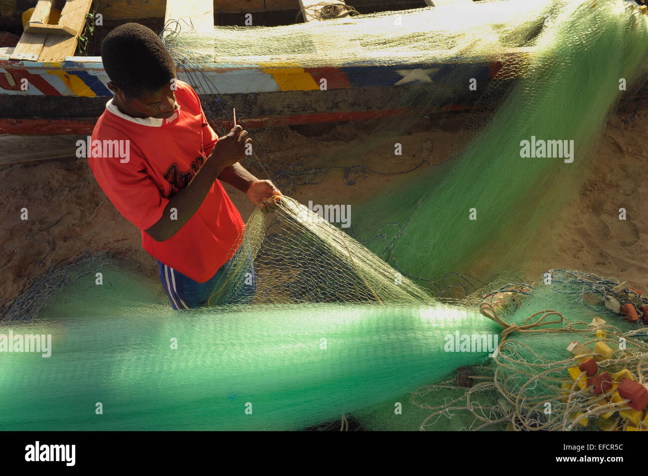 A fisherman mends his nets along the Gold Coast near Accra, Ghana, West ...
