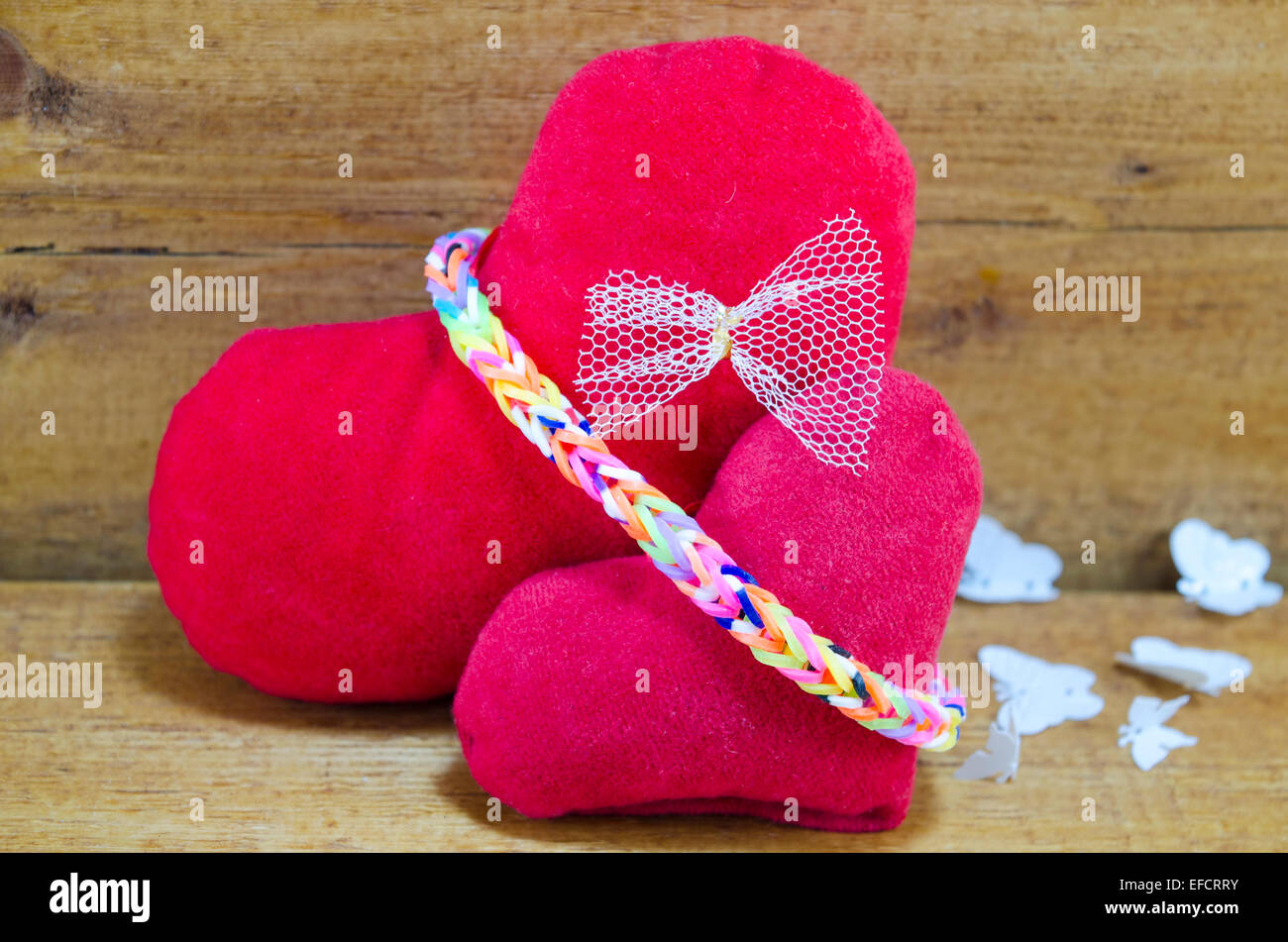 Two stuffed hearts on a wooden surface with paper butterflies in the ...