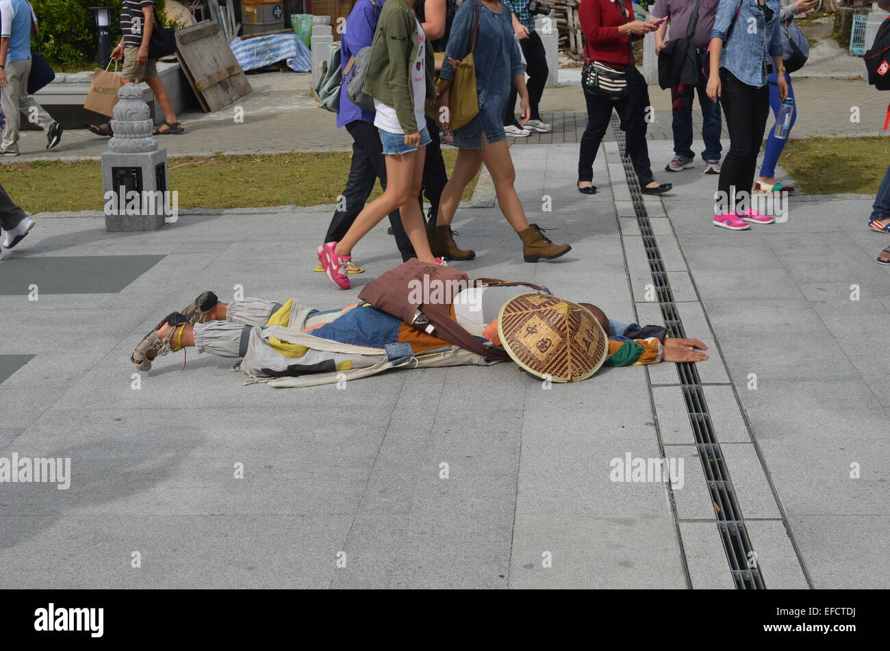 A Chinese monk lays on the sidewalk in lantau island, Hong Kong as part ...