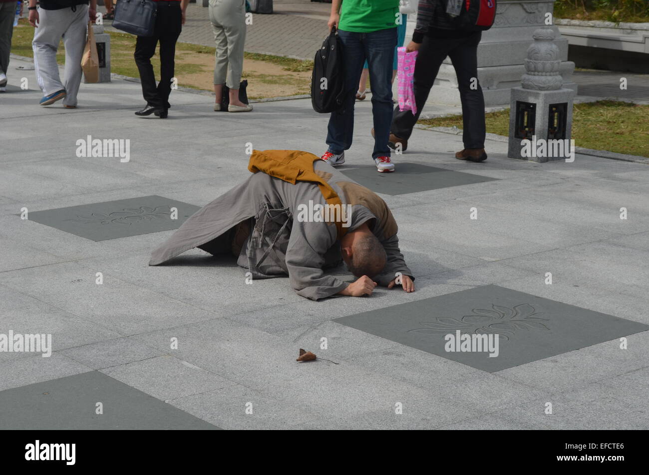 A Chinese Monk crawling on a sidewalk on Lantau Island in Hong Kong ...