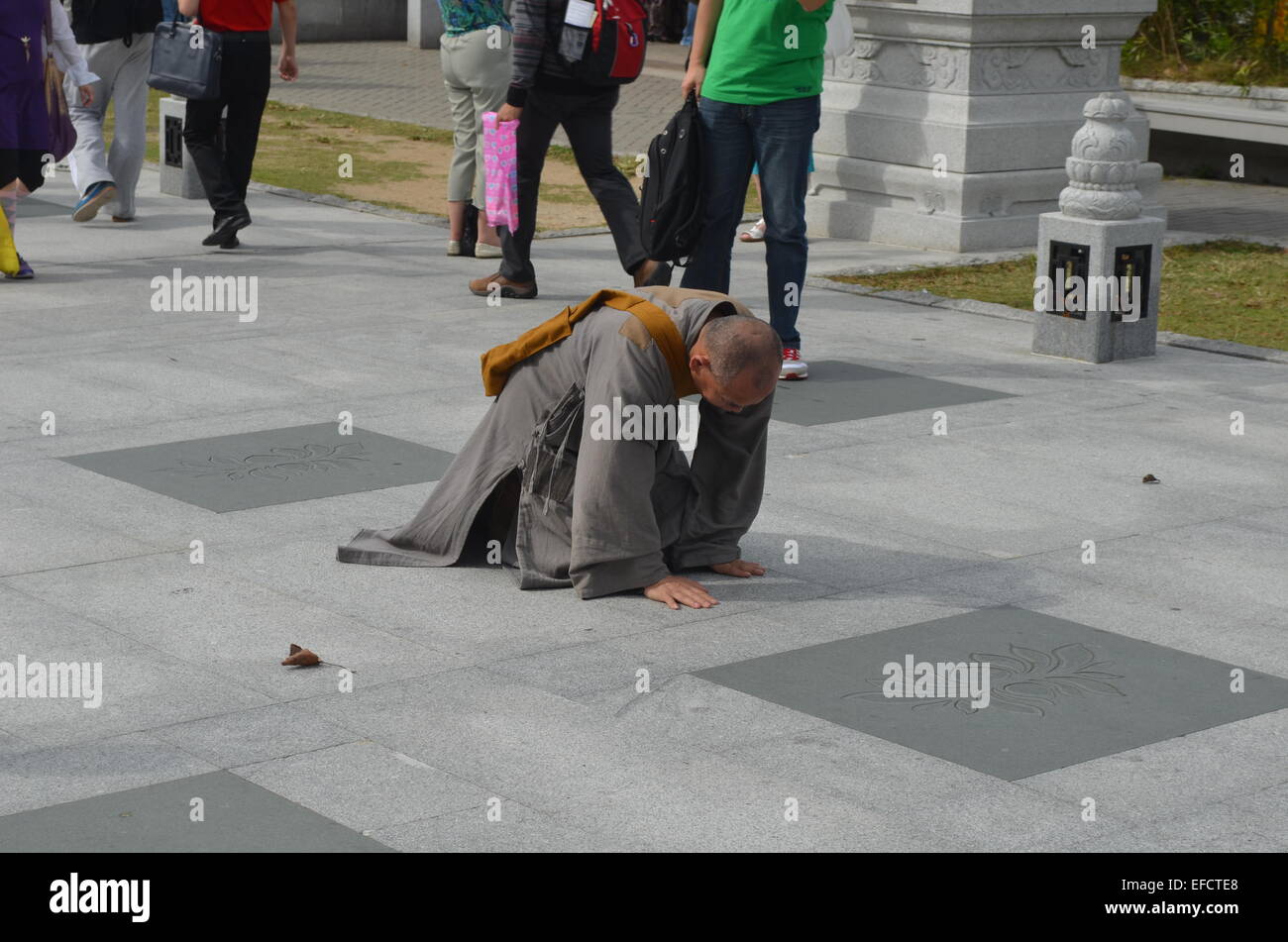 A Chinese Monk crawling on a sidewalk on Lantau Island in Hong Kong ...