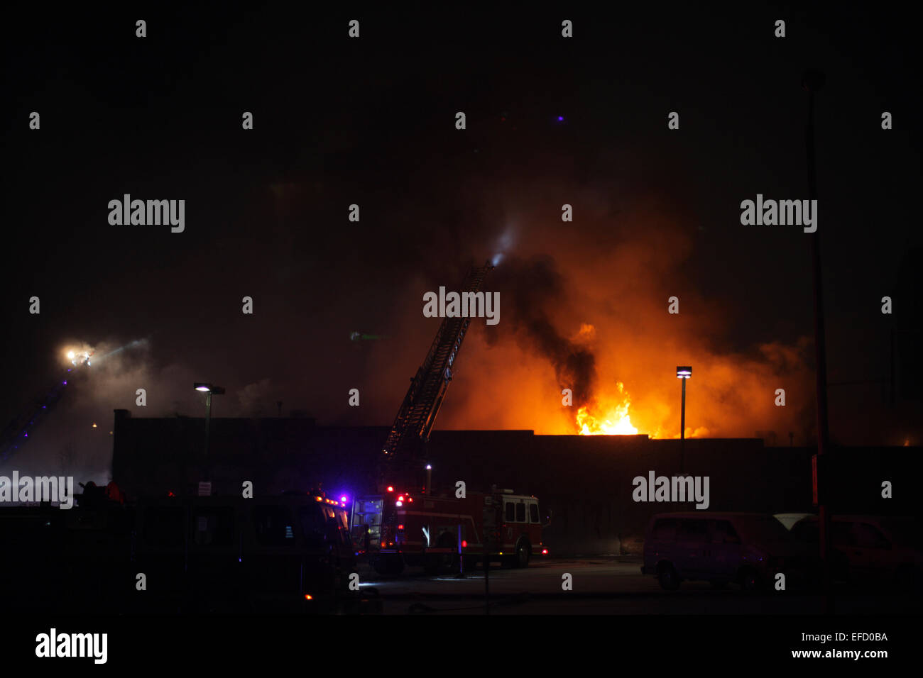 Fire begins to overtake the roof of a nightclub during a nighttime fire ...