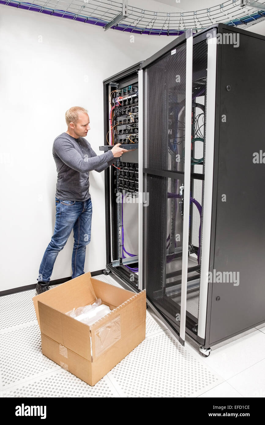 IT engineer installs network switch in datacenter Stock Photo - Alamy