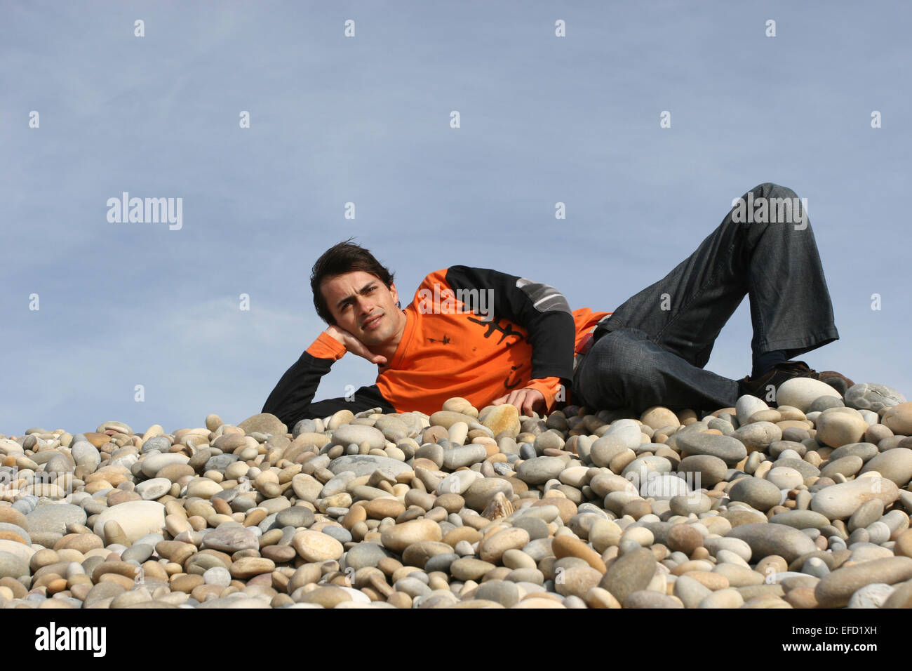 young casual man leaning on one hand at the beach Stock Photo - Alamy