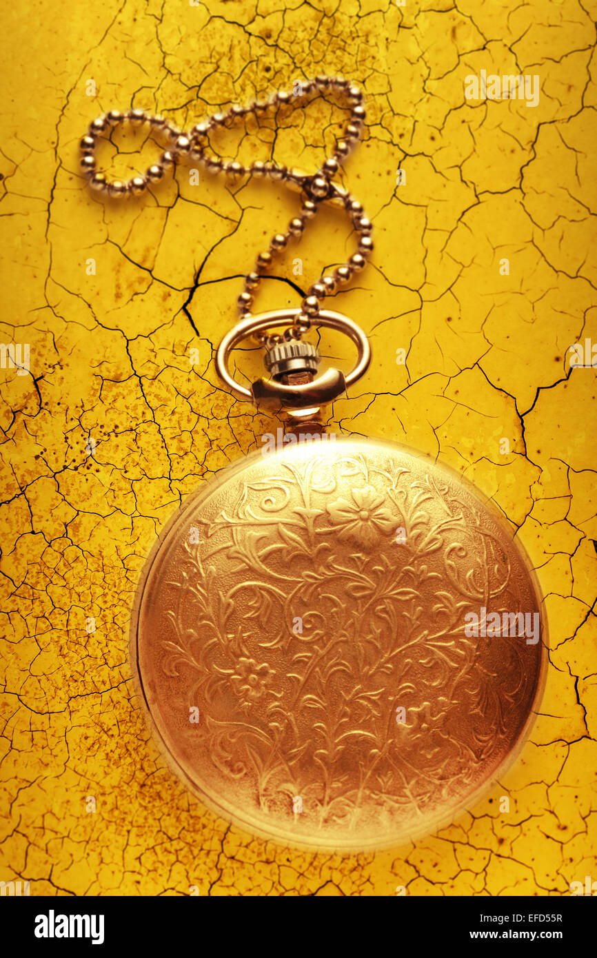 Golden pocket watch with chain on cracked background Stock Photo - Alamy