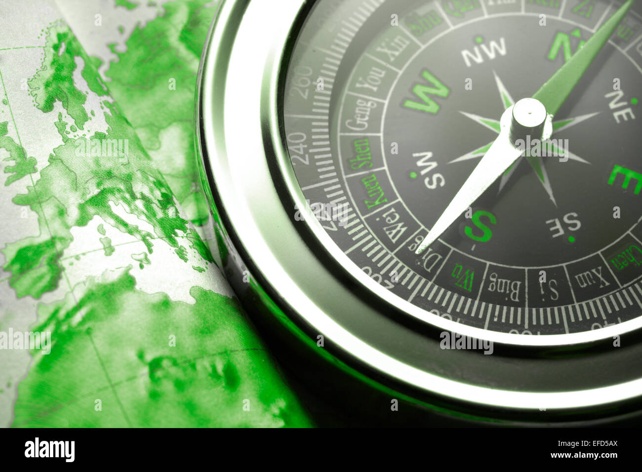 Compass on map background in green toning Stock Photo - Alamy