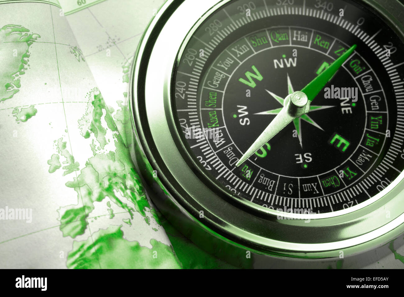 Compass on map background in green toning Stock Photo - Alamy