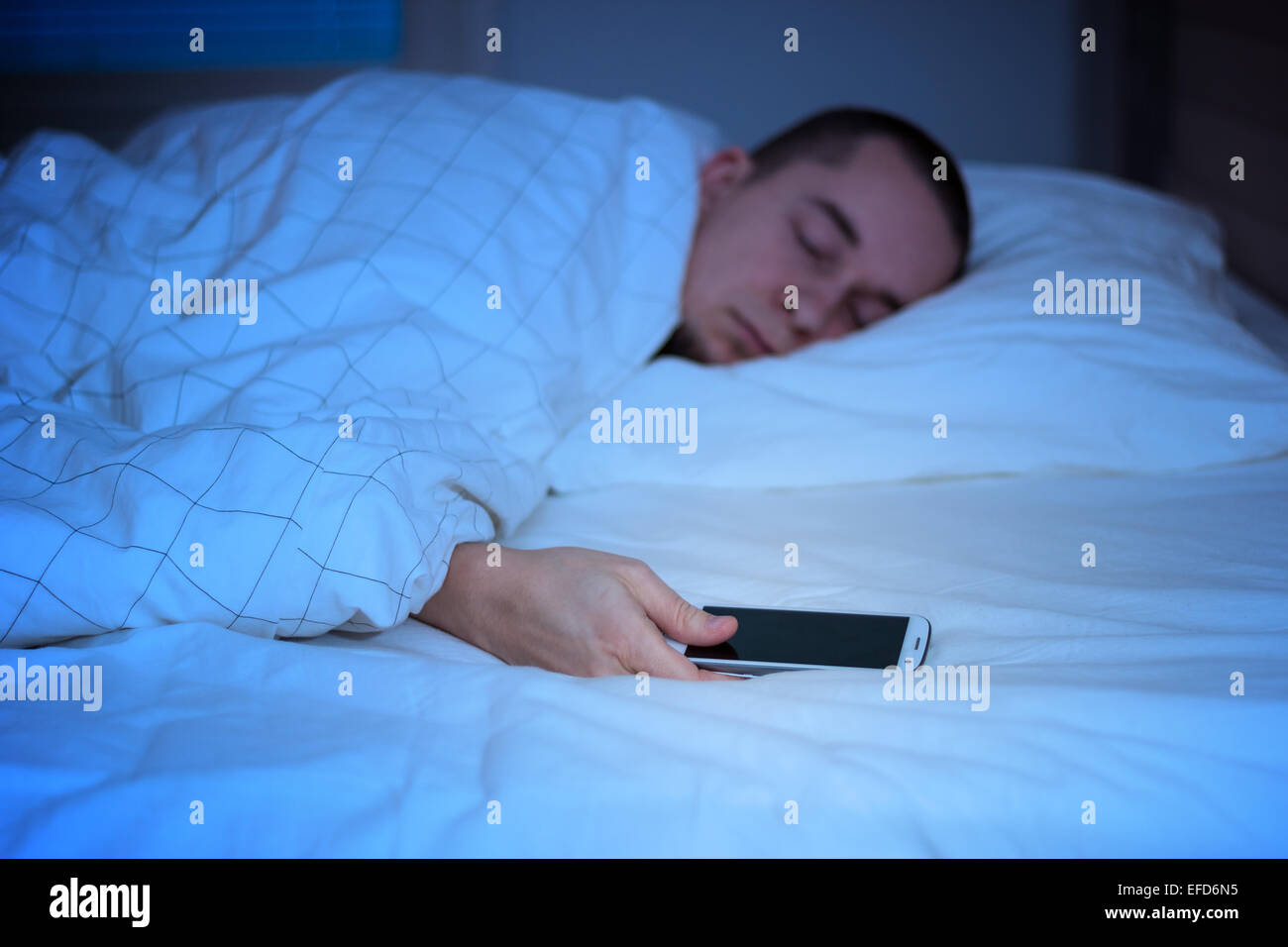 Man sleeping in bed and holding a mobile phone. Concept photo of ...
