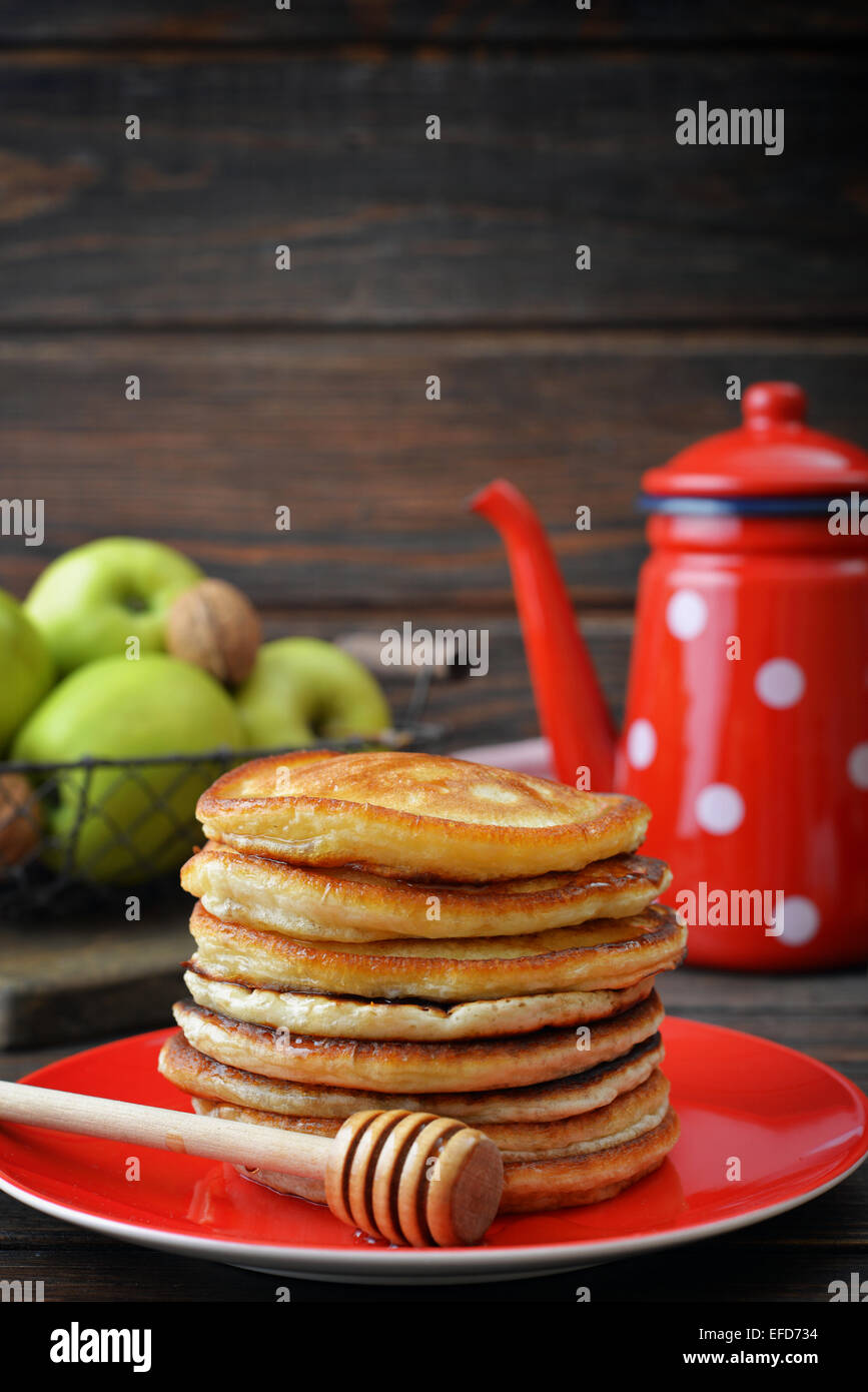 Stack of pancakes on plate with vintage teapots and fresh apples on ...