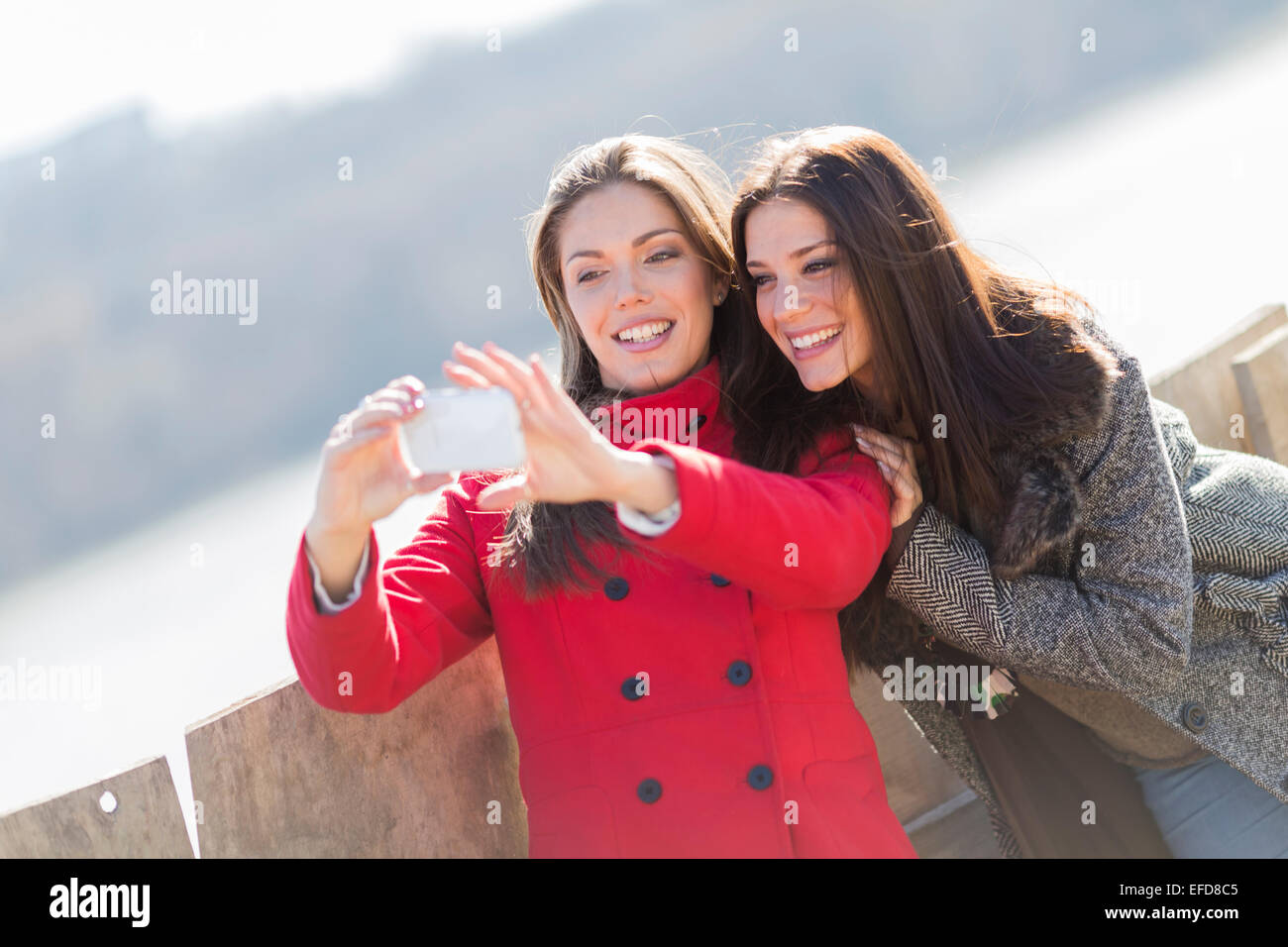 Happy young women taking photo with mobile phone Stock Photo - Alamy