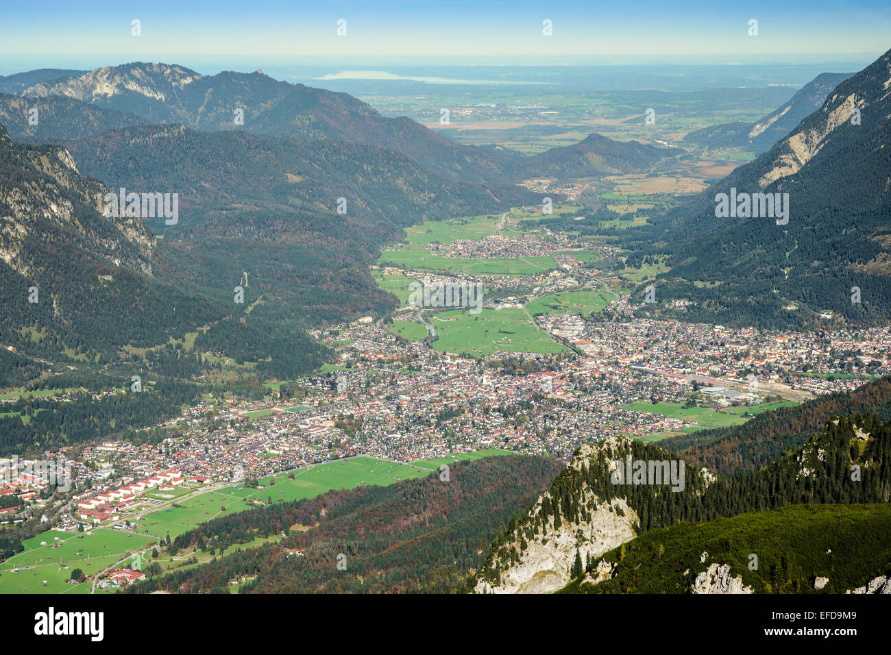 Aerial view of green valley with small town on rim of Alps mountains ...