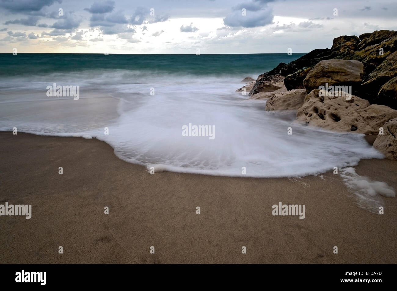 Breaking wave beach sand and breakwater Stock Photo - Alamy