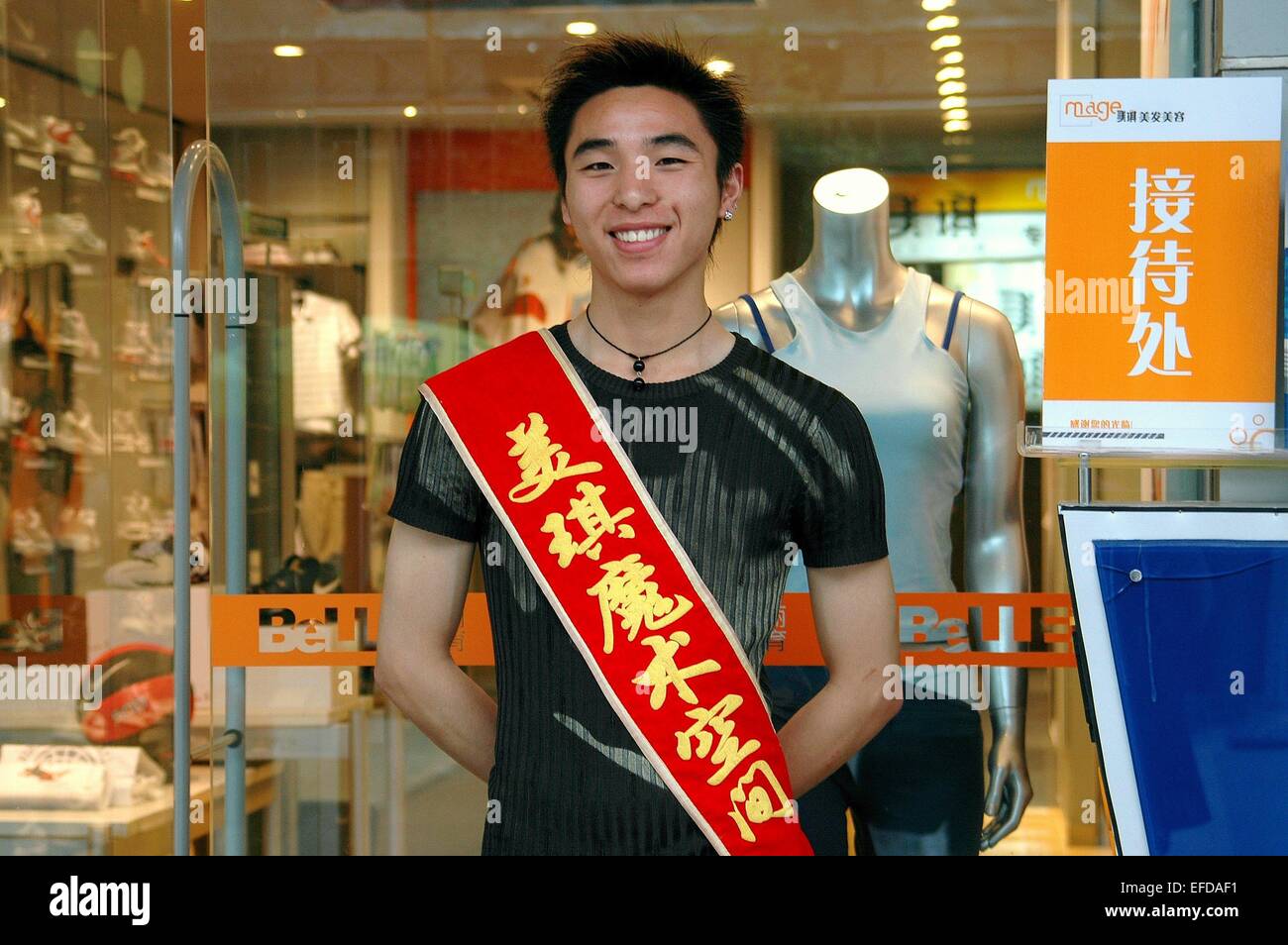 Chengdu, China: Smiling sales clerk wearing a red sash in the doorway ...