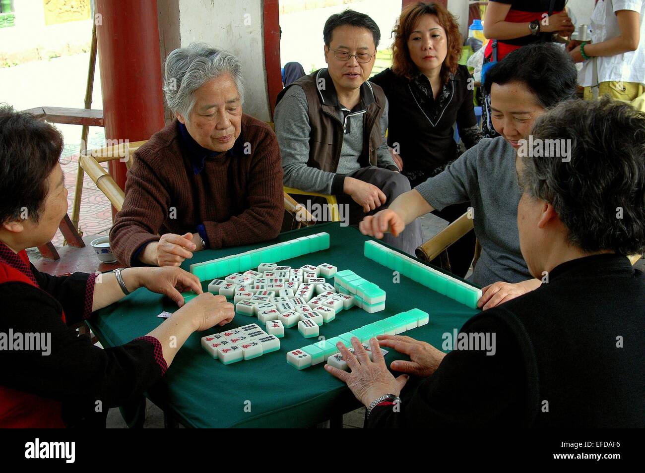 Chengdu, China: Onlookers watching four women playing a game of mahjong ...