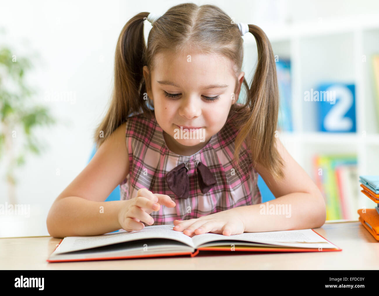Cute kid girl reading story from big book in nursery Stock Photo - Alamy